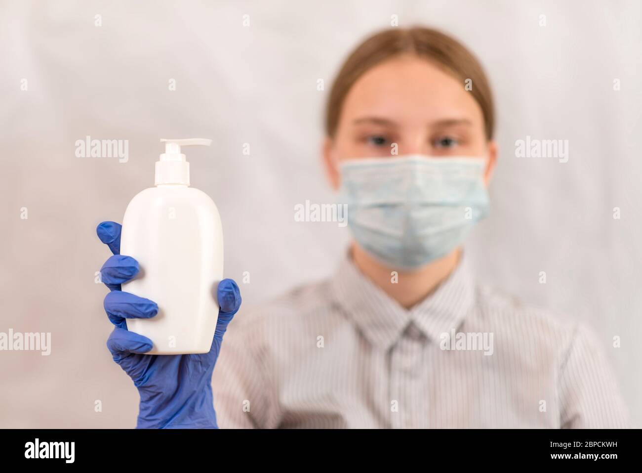 close-up focus on a gloved hand with bottle of antiseptic liquid soap ...