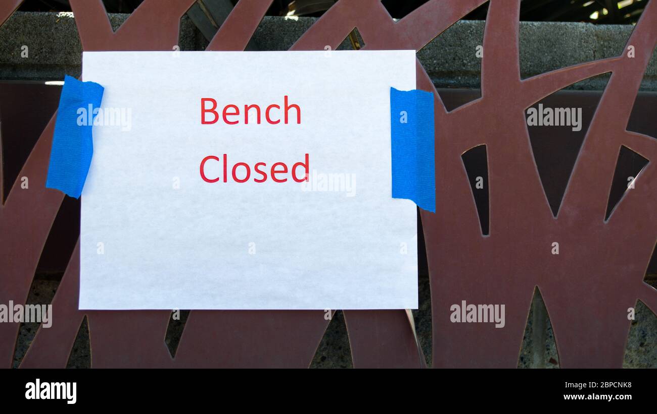 white paper sign saying "Bench Closed" taped to a park bench during ...