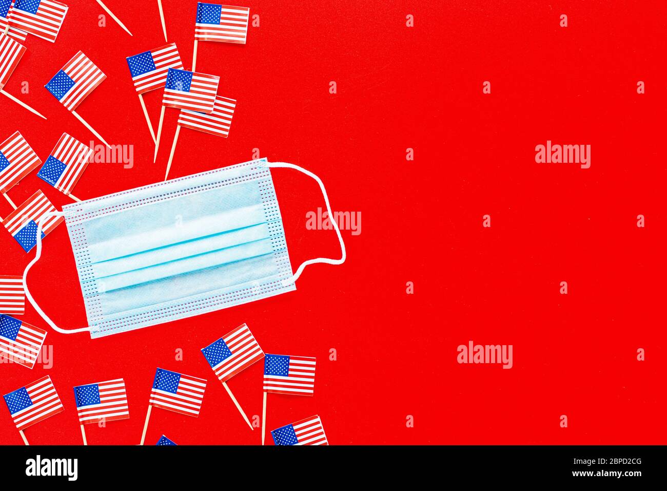 July 4th. USA flags and medical mask on red background. Independence ...