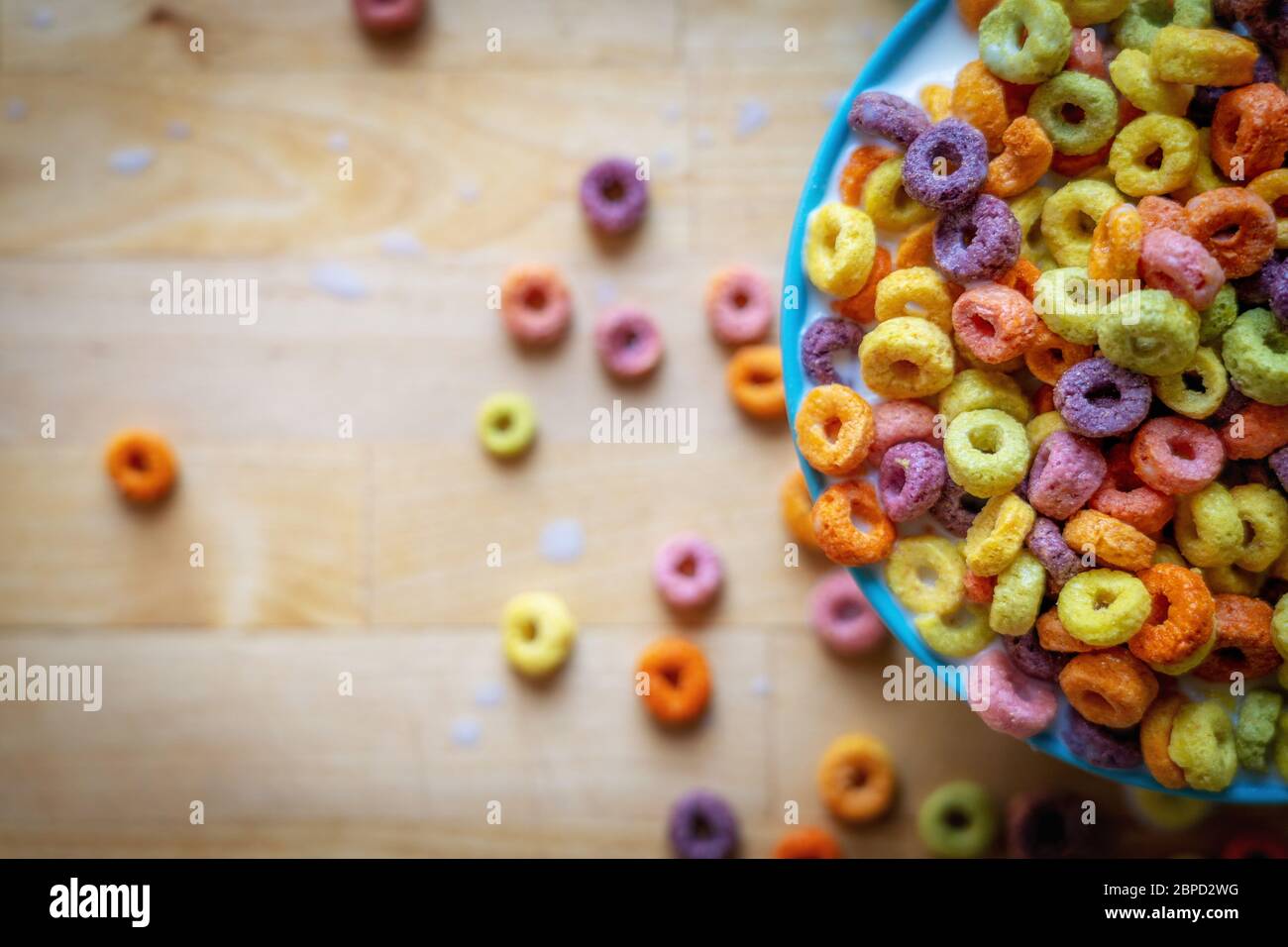 Colourful bowl of cereal spilling over wooden table top, flat lay Stock ...