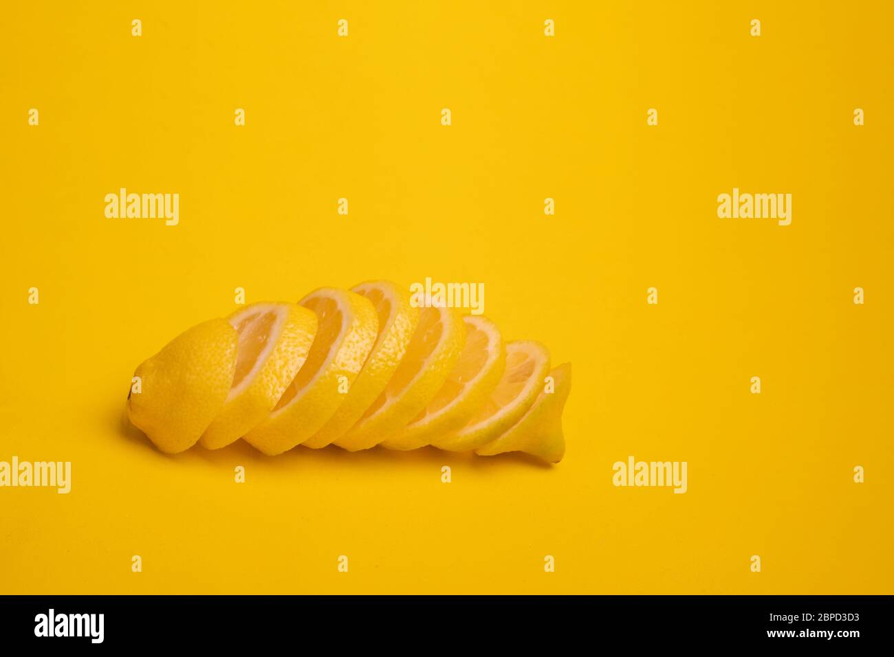 A lemon cut into slices lies on a yellow background Stock Photo - Alamy