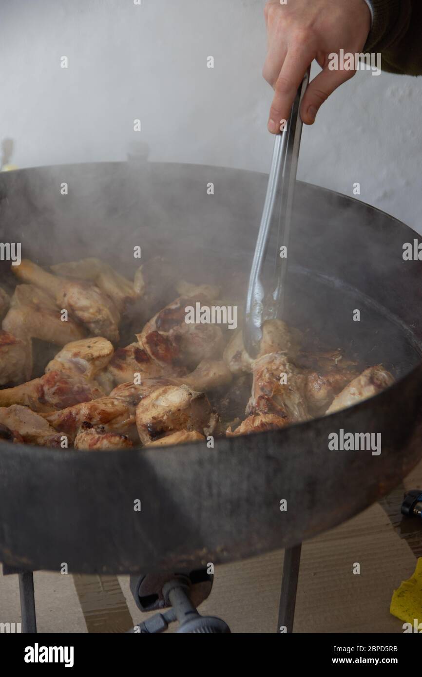 Chicken cooked with beer by turning it with a tongs Stock Photo - Alamy