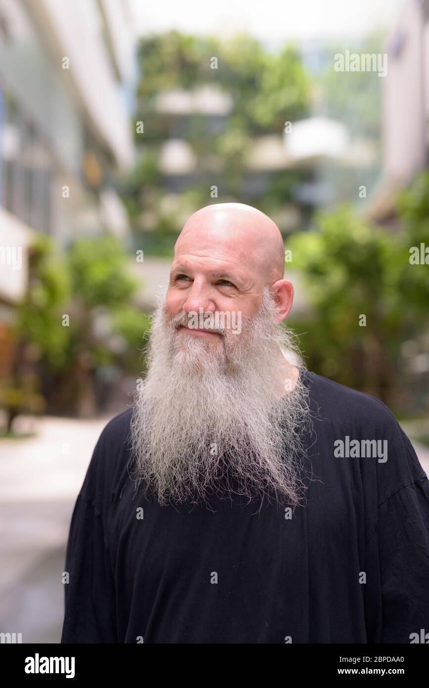 Face of happy mature handsome bald bearded man thinking with nature in ...