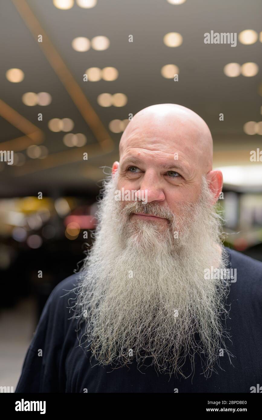 Face of mature handsome bald bearded man thinking in the city outdoors ...