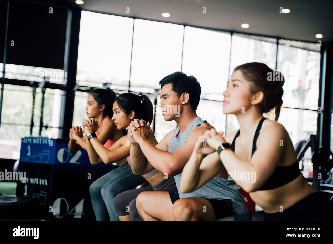 Group of athletic young Asian people in sportswear doing squat and ...