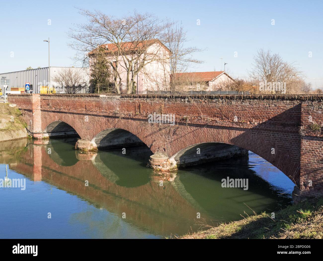 brick bridge with three arches crosses a small river in the countryside ...