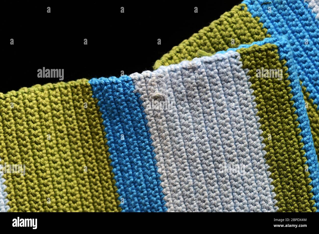 Fragment of crocheted fabric from green, blue and light blue threads ...