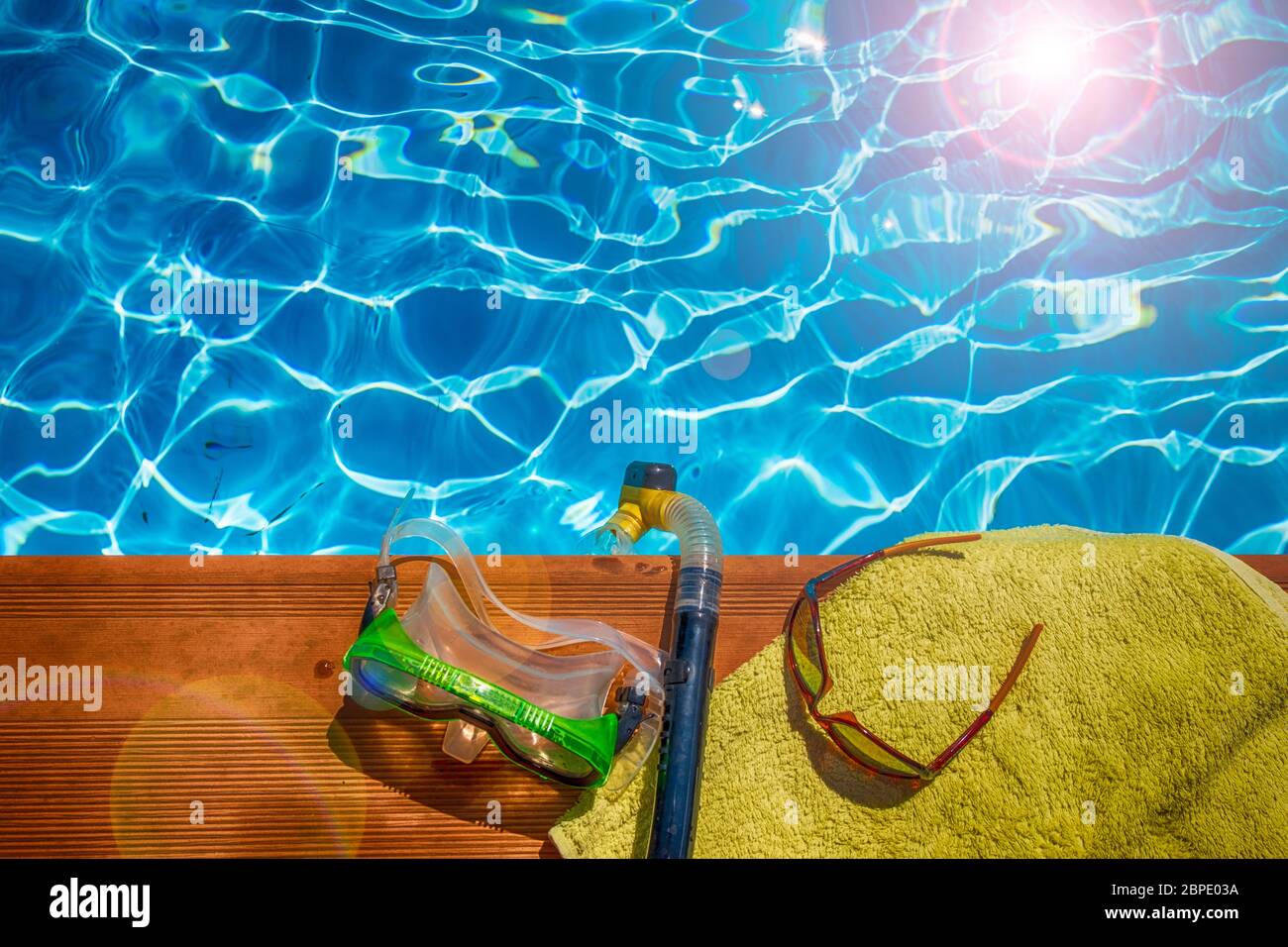 Sun flare in sunlit swimming pool with snorkel mask, sunglasses and ...