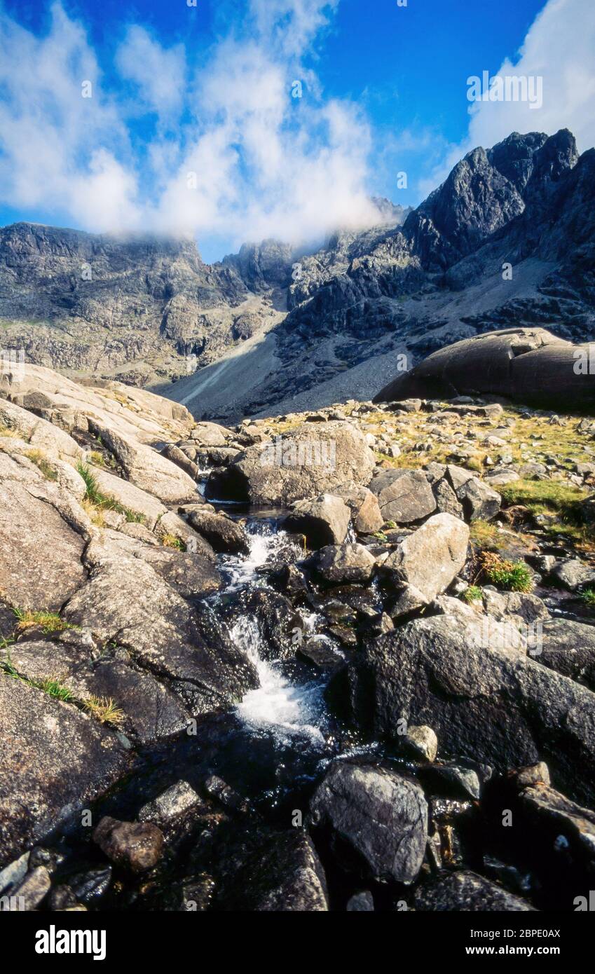 Tumbling mountain stream emerging from the glaciated mountain corrie of ...