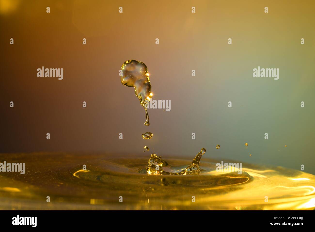 Falling water droplet against coloured background forming shape ...