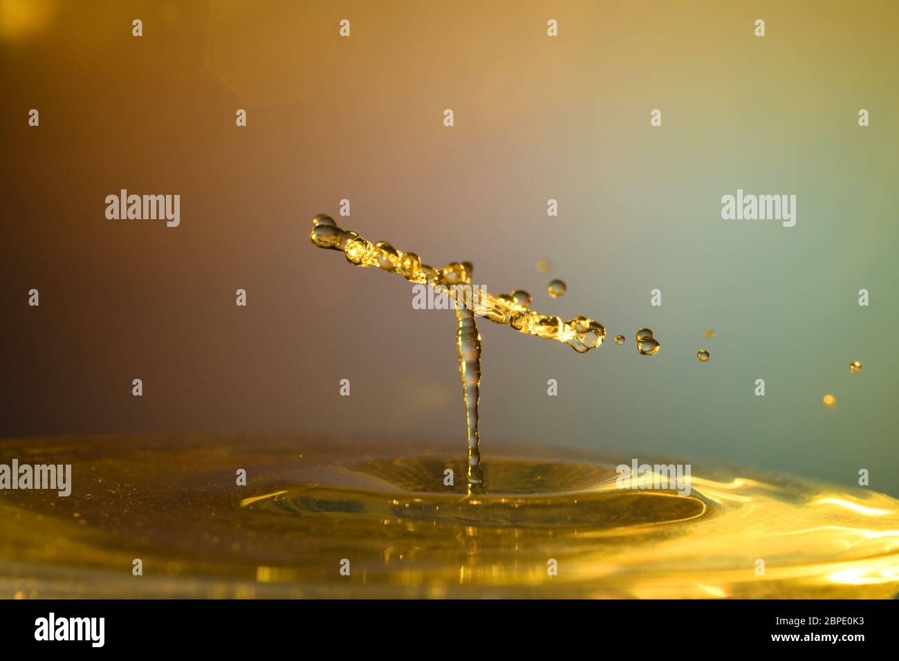Falling water droplet against coloured background forming shape ...