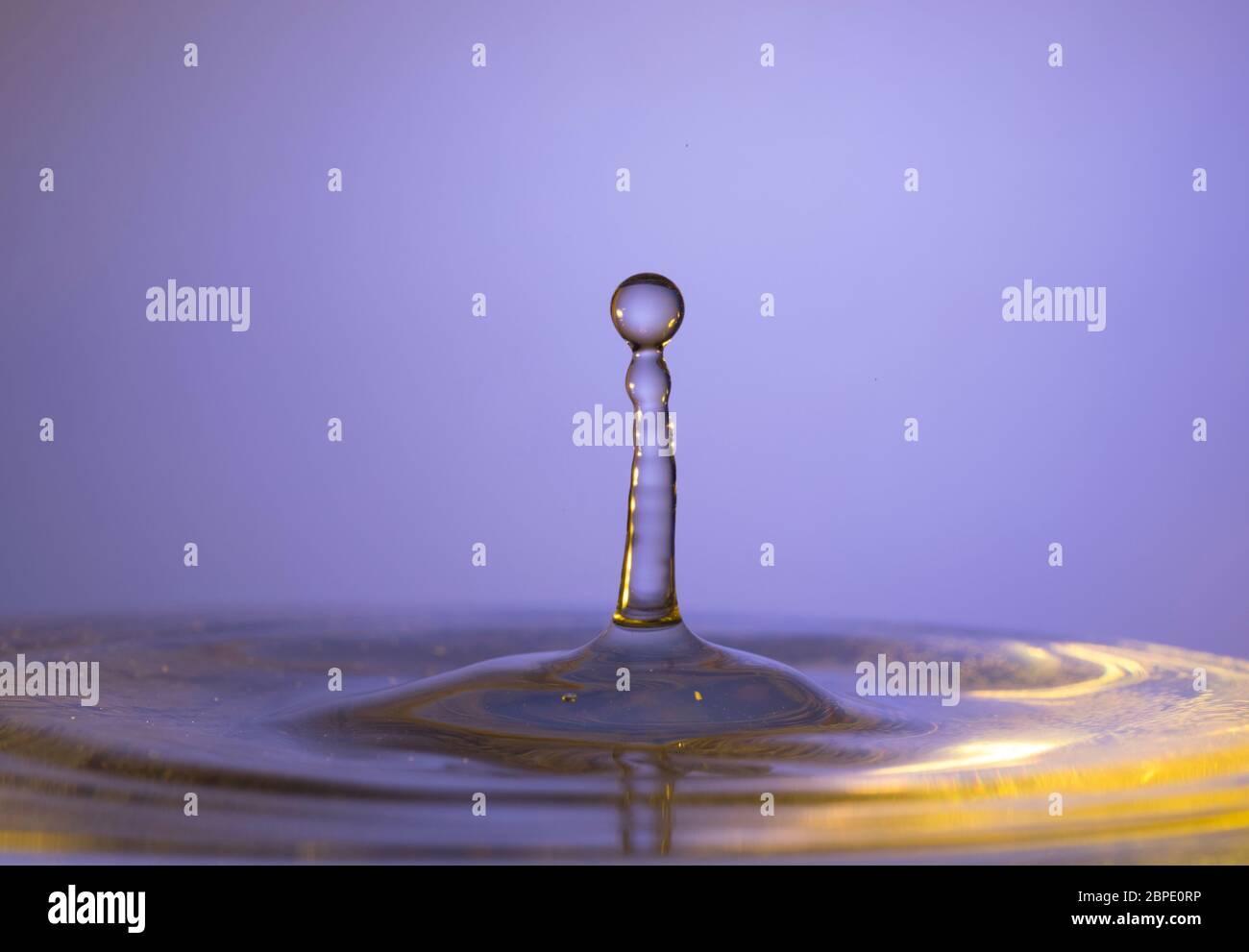 Falling water droplet against coloured background forming shape ...
