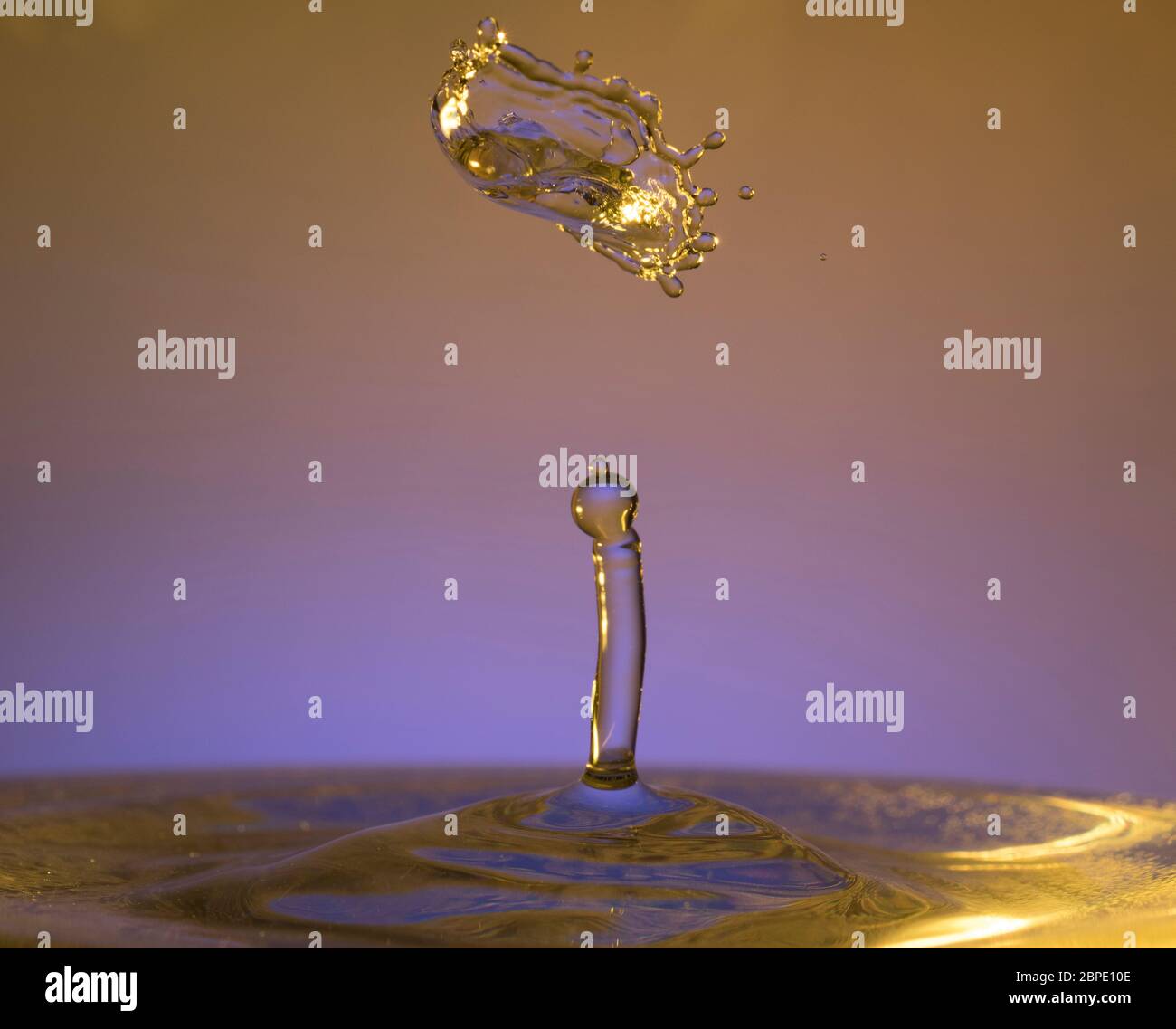 Falling water droplet against coloured background forming shape ...