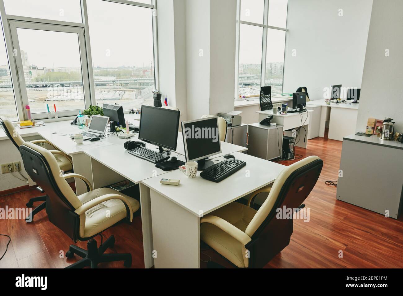 Interior of empty modern office with desktop computers on tables placed ...