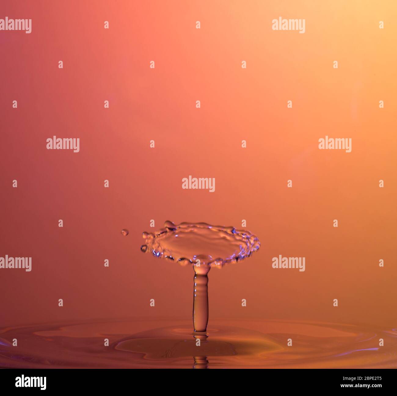 Falling water droplet against coloured background forming shape ...