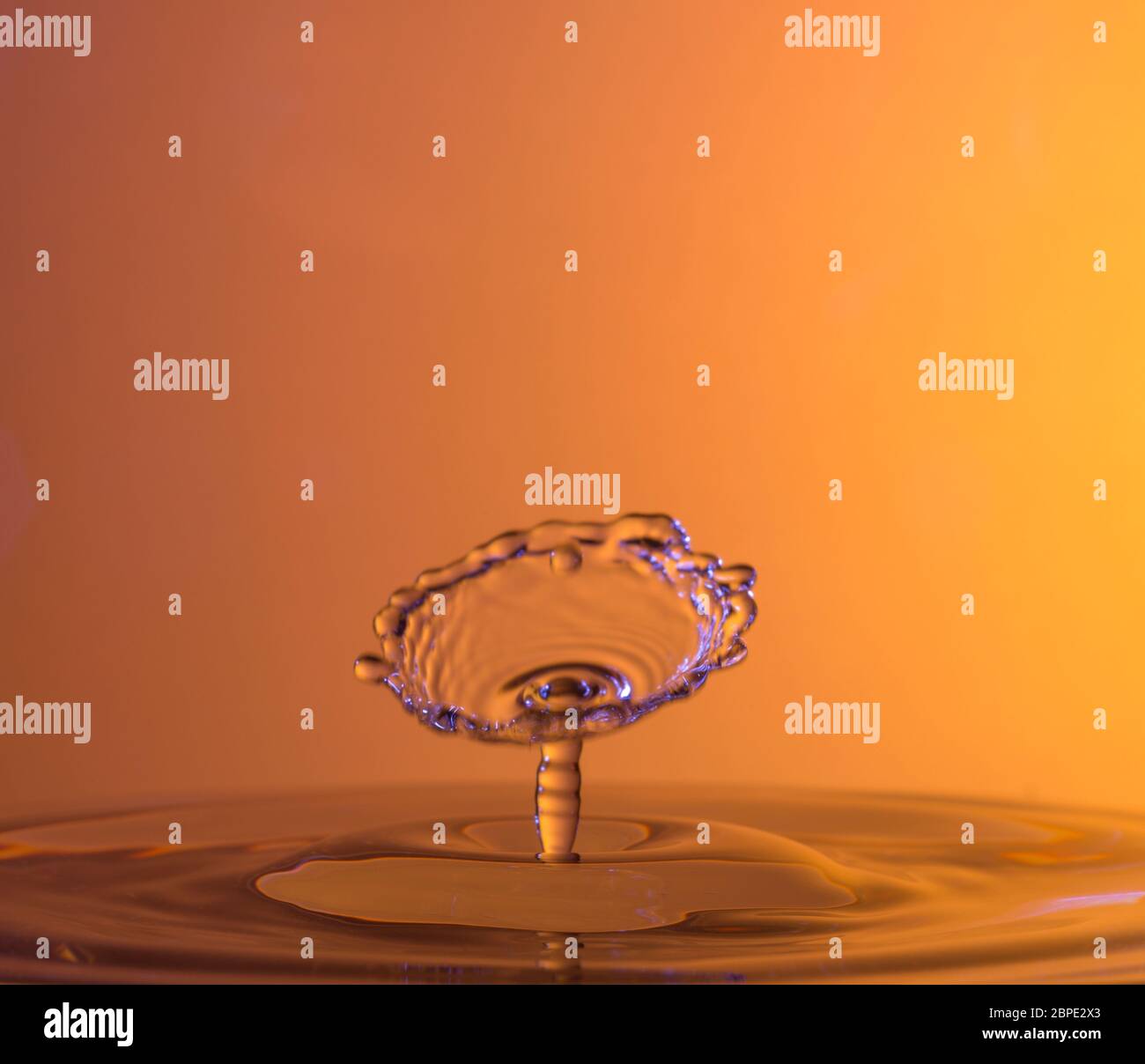 Falling water droplet against coloured background forming shape ...