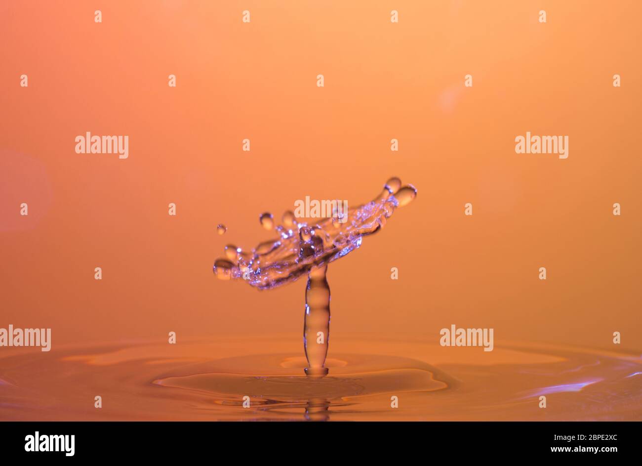 Falling water droplet against coloured background forming shape ...