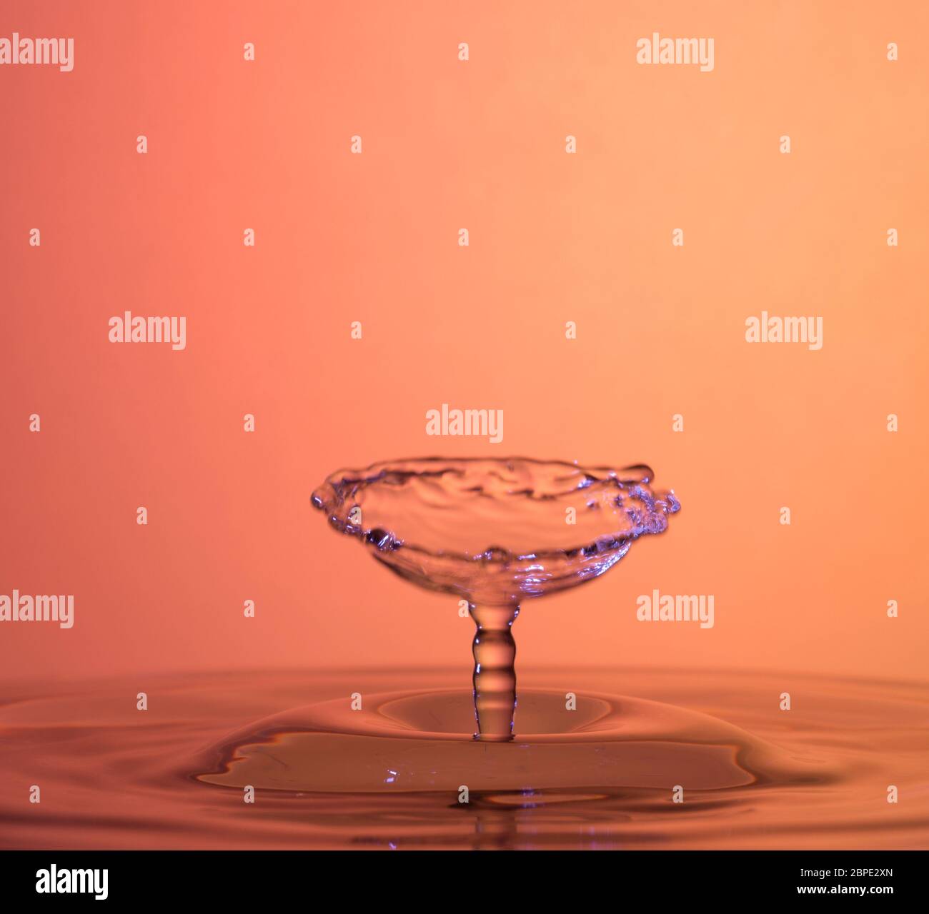 Falling water droplet against coloured background forming shape ...