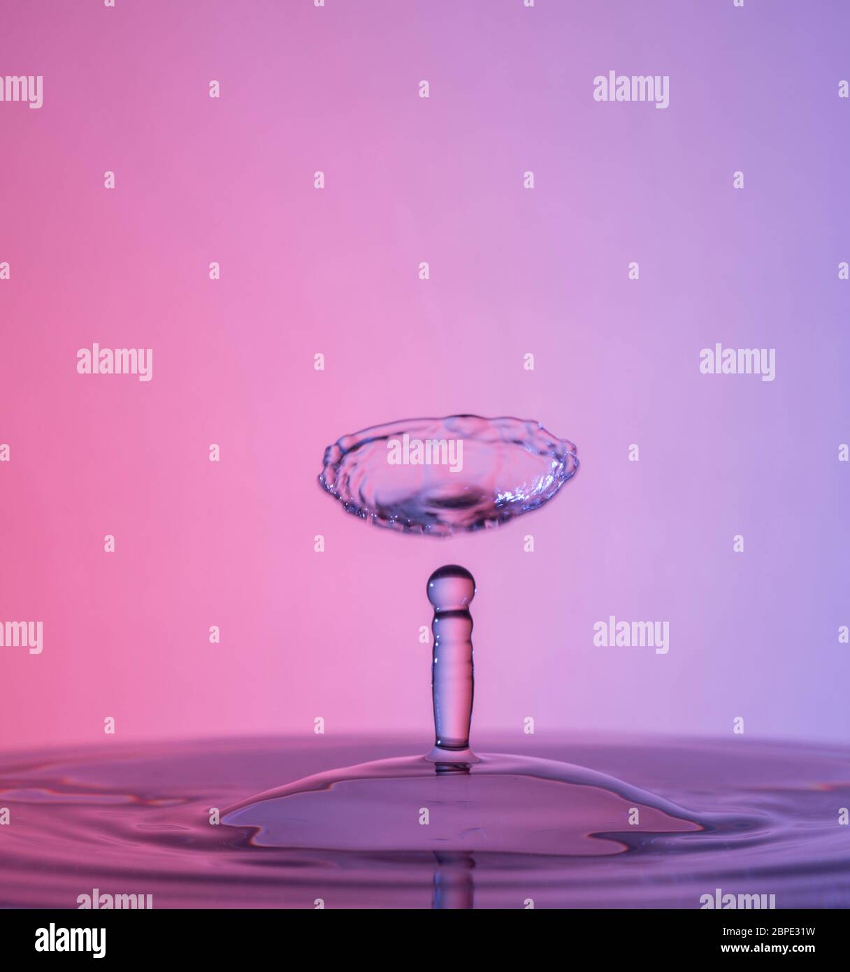 Falling water droplet against coloured background forming shape ...