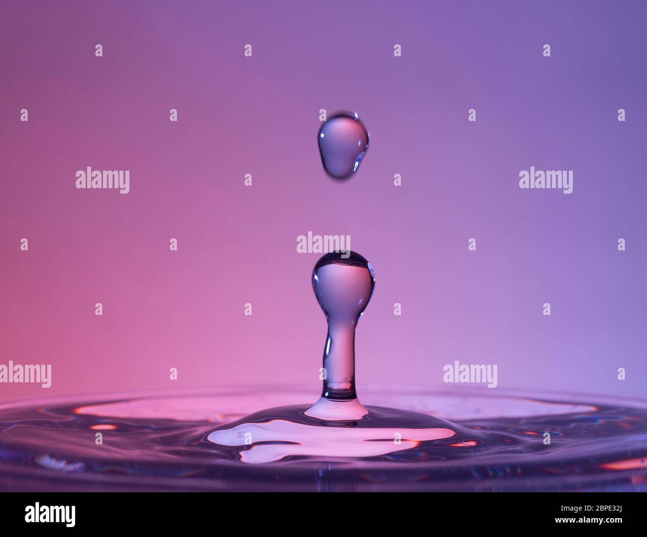 Falling water droplet against coloured background forming shape ...
