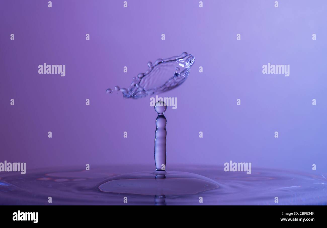 Falling water droplet against coloured background forming shape ...