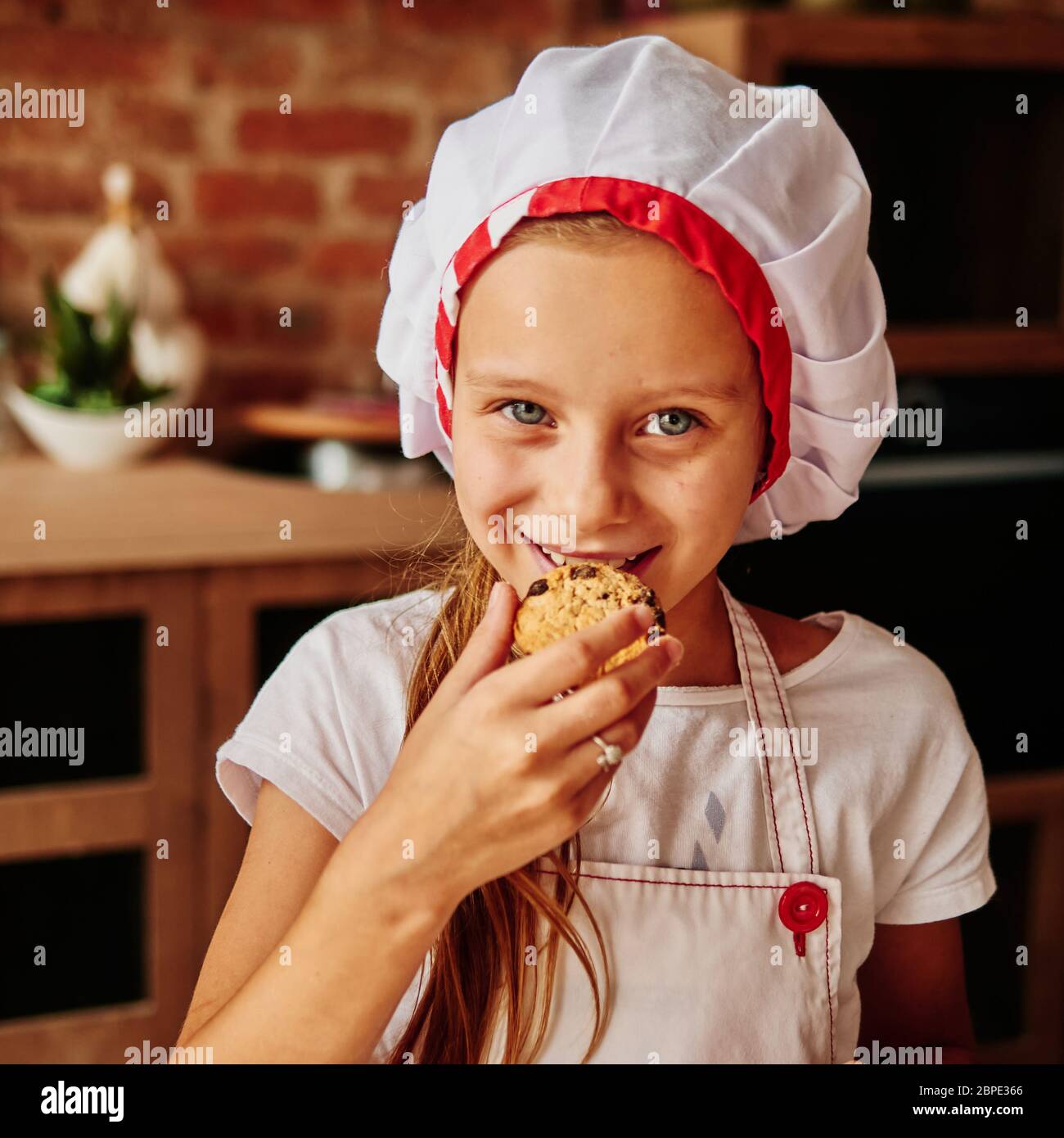 Girl in cooking chef clothes eating cake. Girl at the kitchen. Family ...
