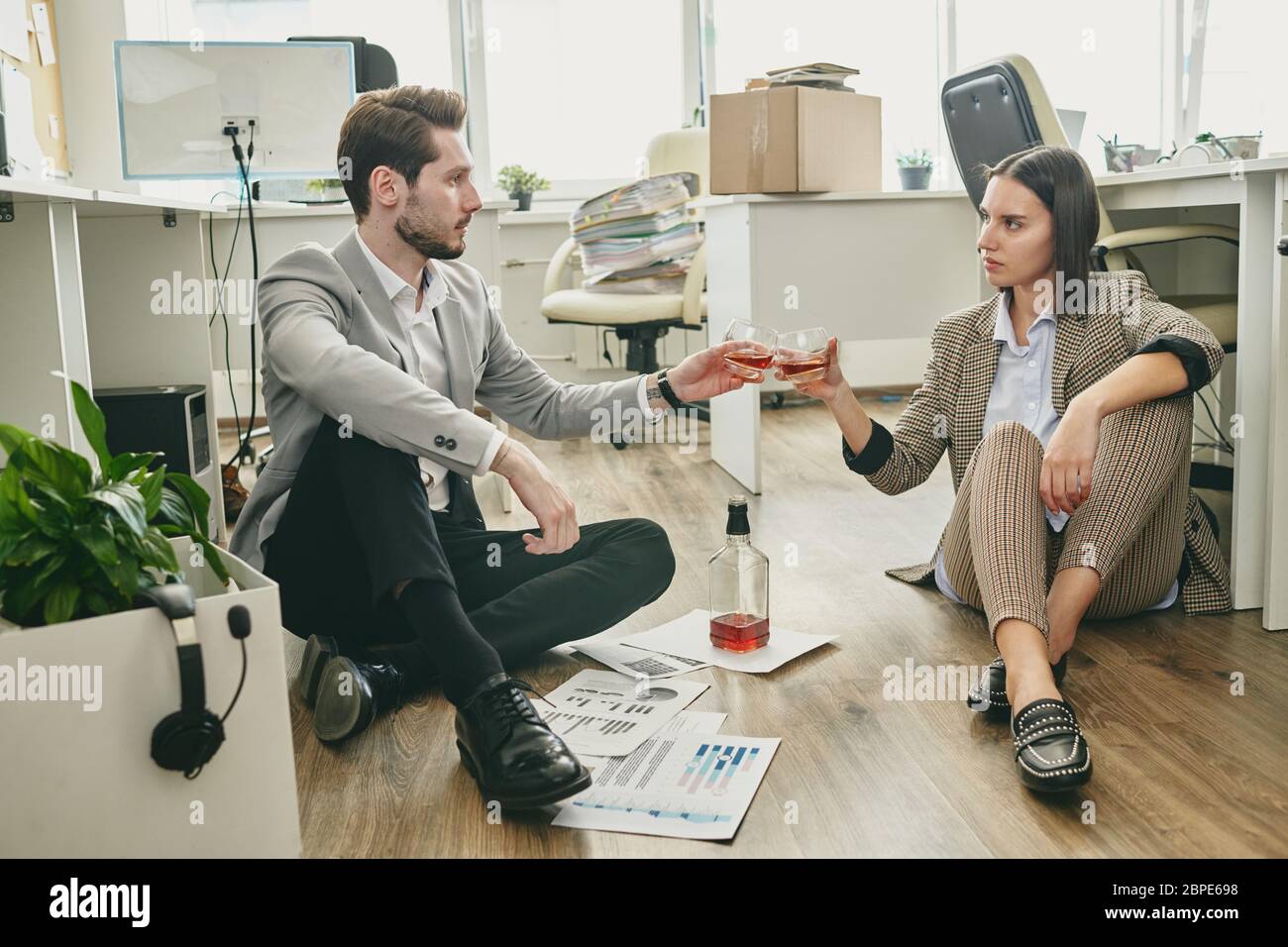 Desperate office people sitting with graph papers on floor and toasting ...