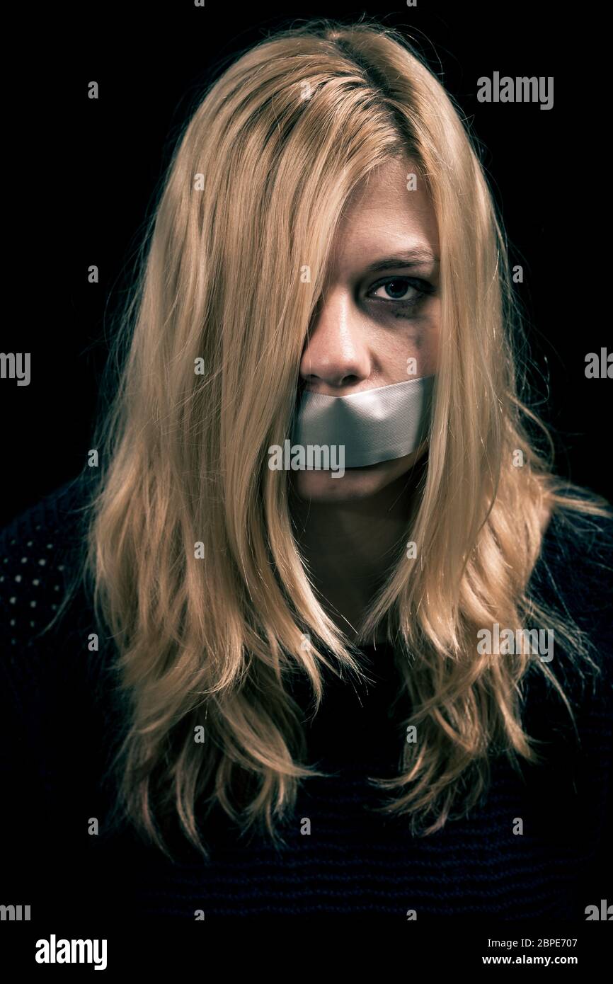 Portrait of scared kidnapped woman hostage with tape over her mouth ...