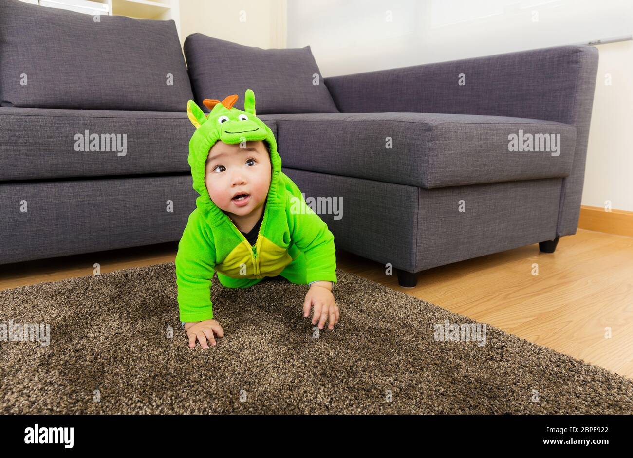 Baby creeping at home with dinosaur dressing Stock Photo - Alamy