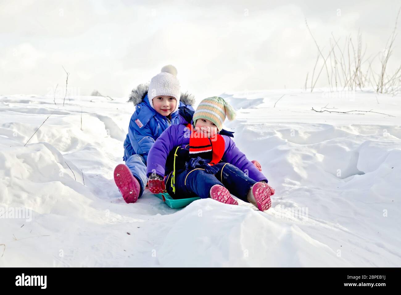 Two little girls on a sled in the snow in the winter Stock Photo - Alamy