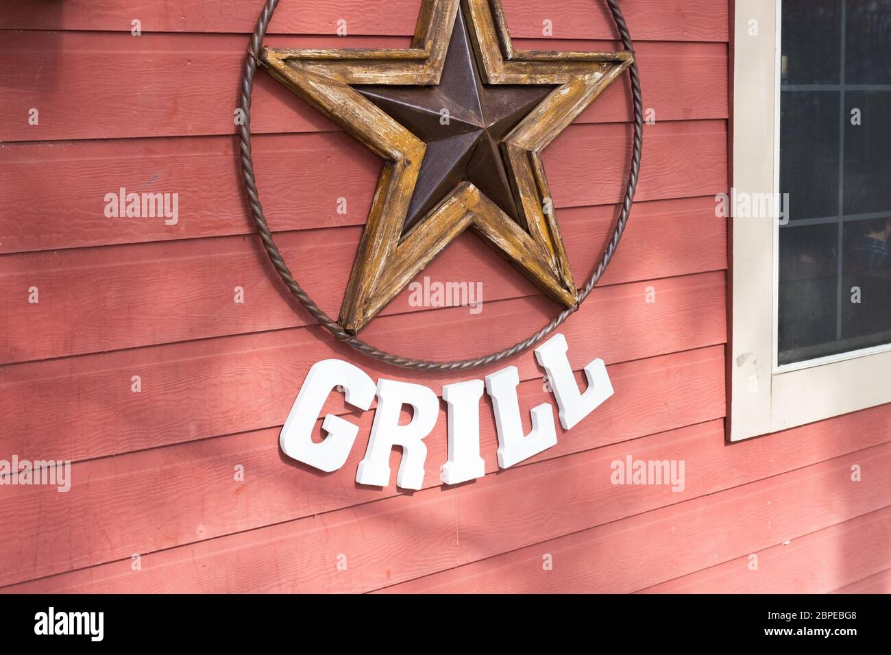Rusty metal star sign hanging on a red wooden wall of a grill place in ...