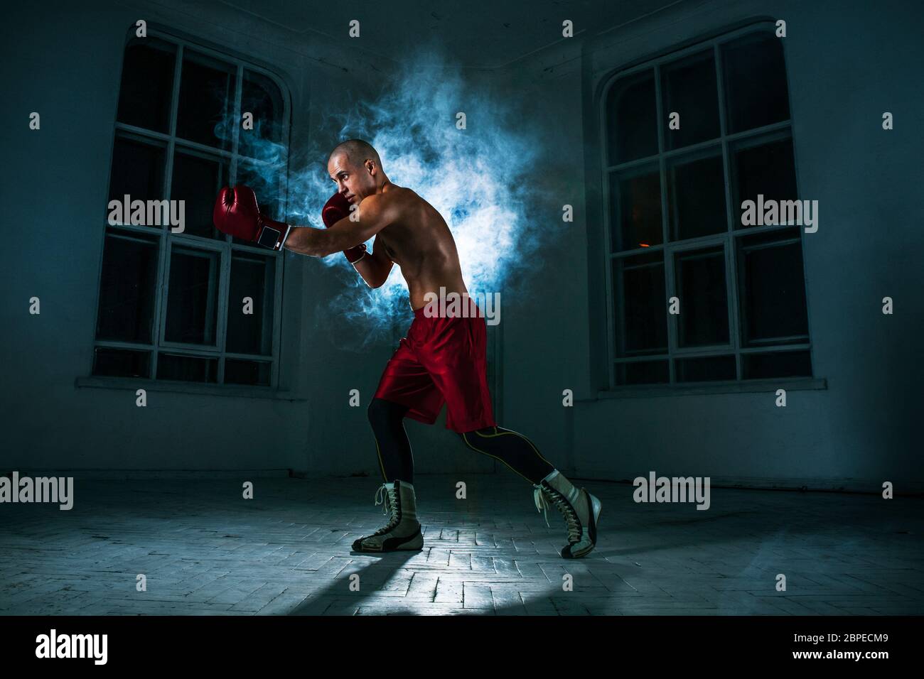 The young male athlete kickboxing on a background of blue smoke Stock ...