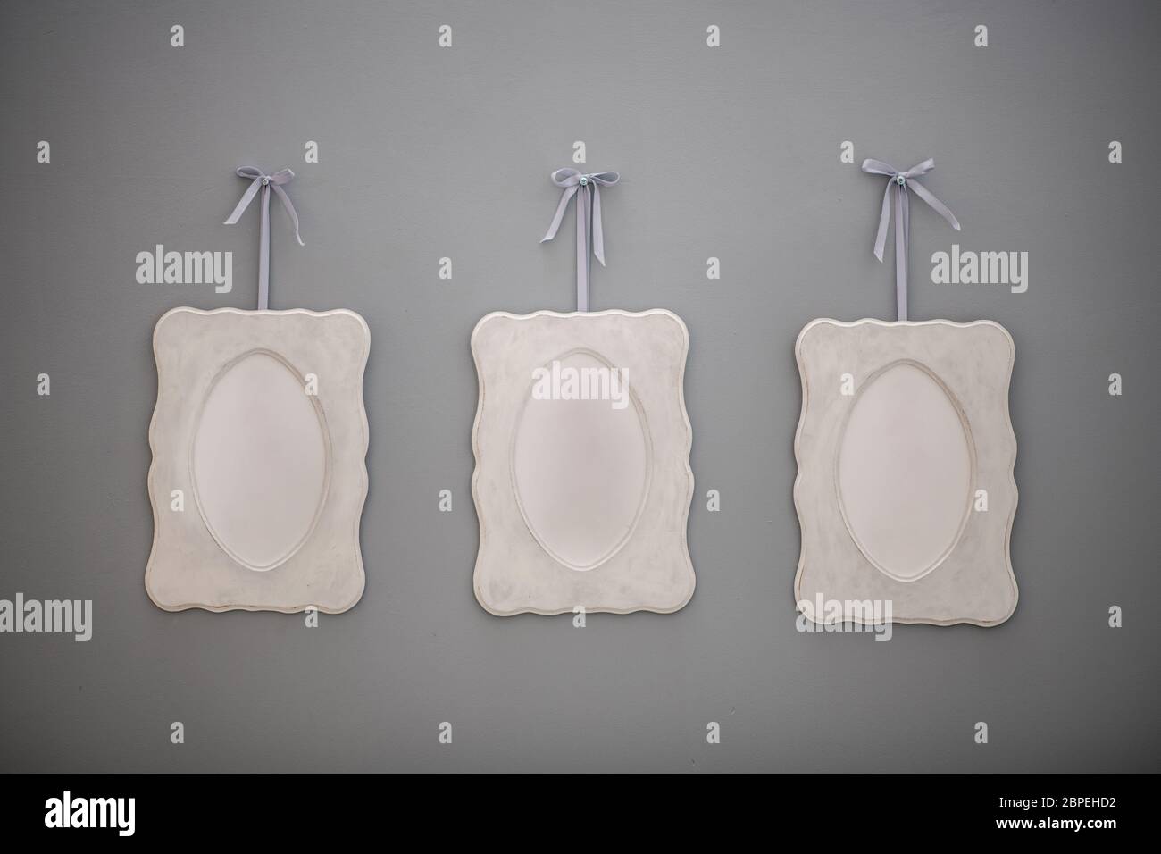 Three empty frames hanged on a grey wall Stock Photo - Alamy