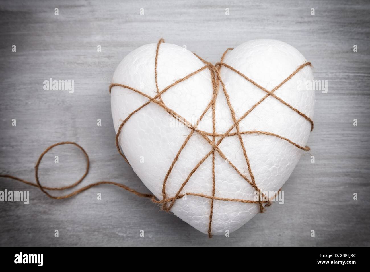 Heart bound by a string on grey rustic background Stock Photo - Alamy