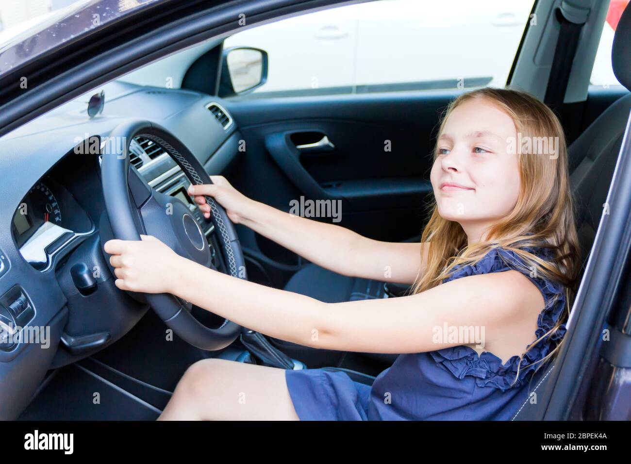 Cute girl driving car with blond long hair Stock Photo - Alamy