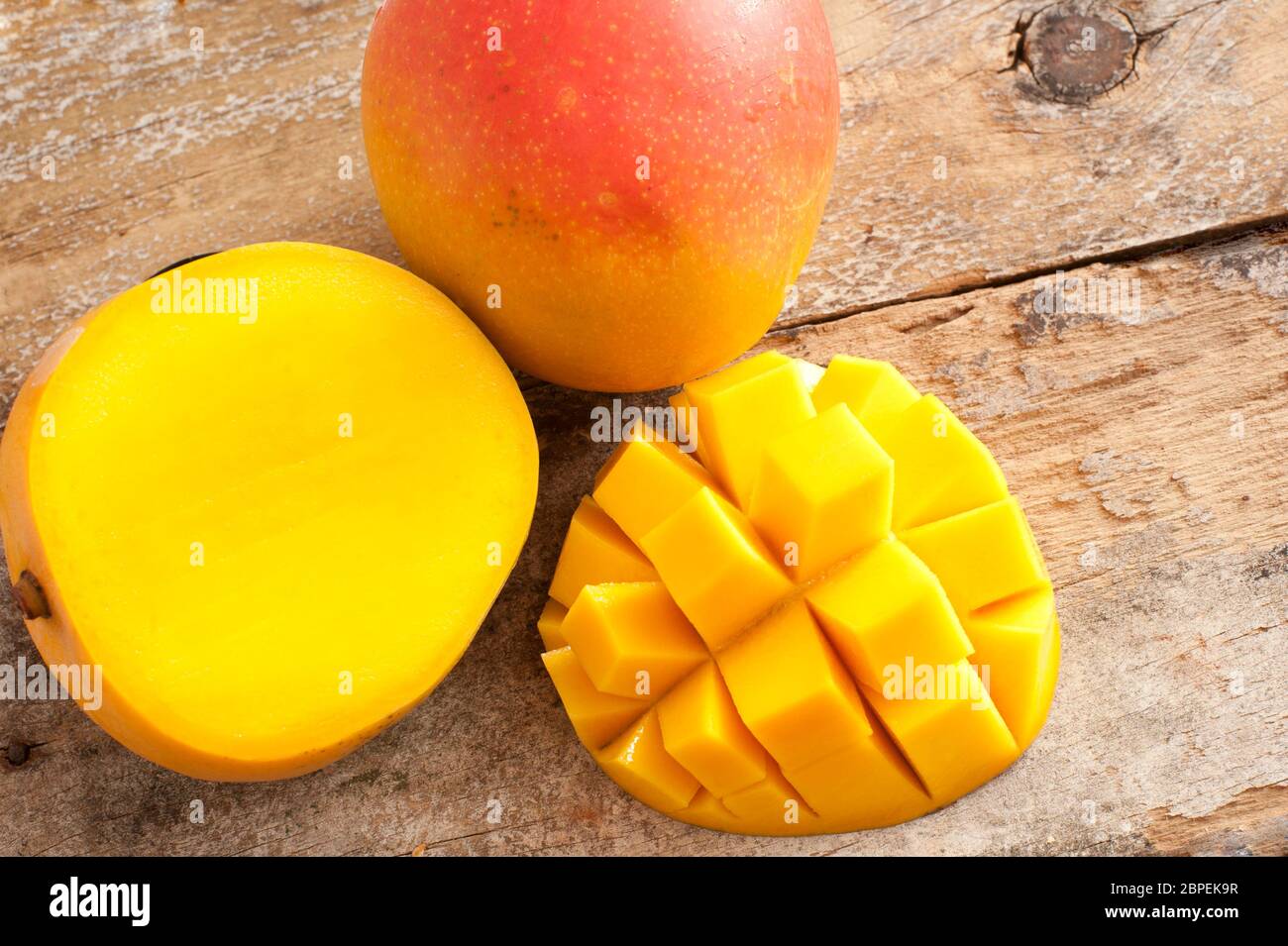 Fresh ripe tropical mango whole and sliced through to show the juicy ...