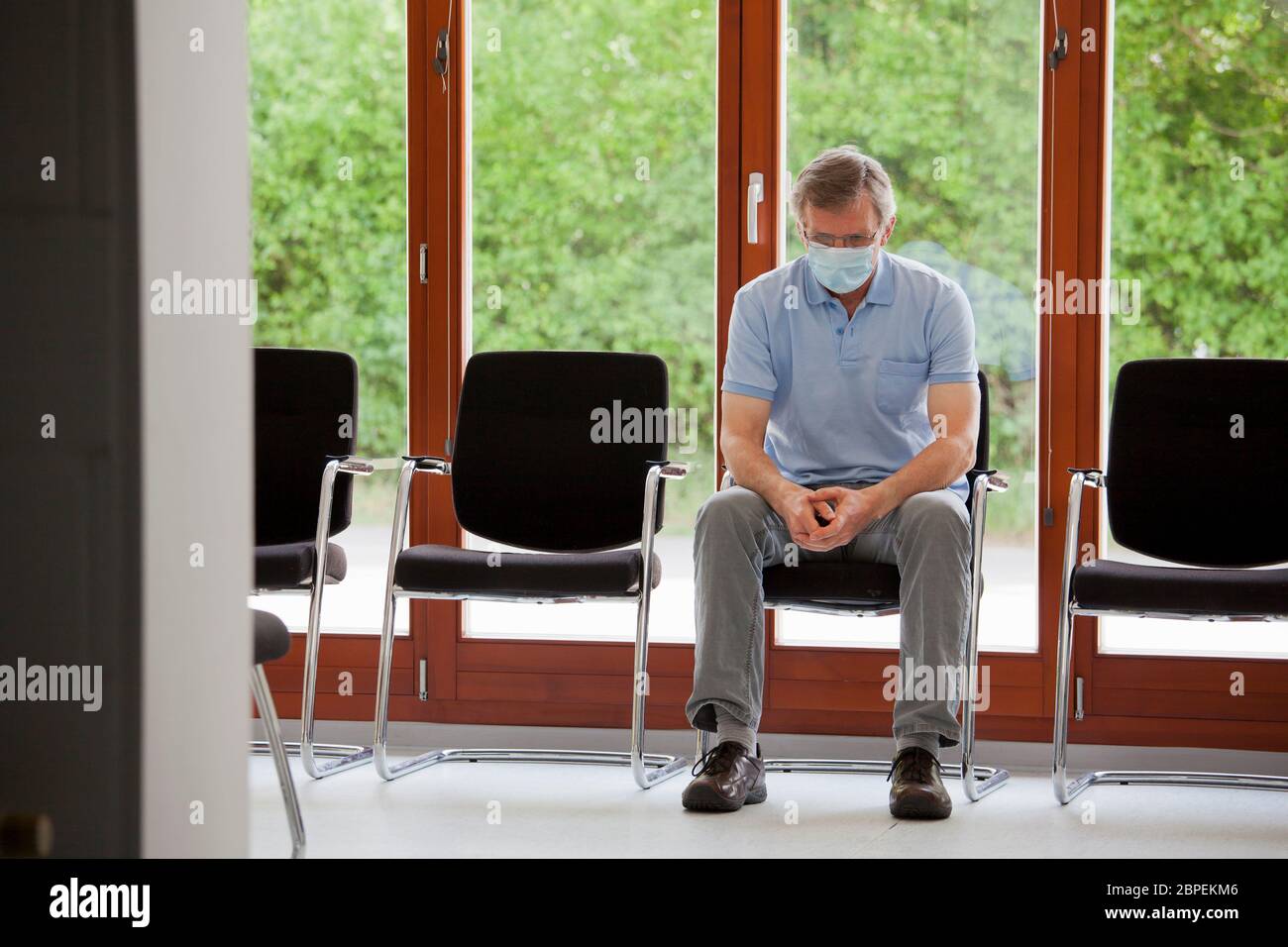 Mature serious patient or visitor alone sitting in an empty waiting ...