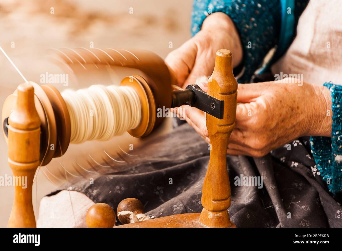 Oldster spinning cotton of traditional form on a craftsmen's market ...
