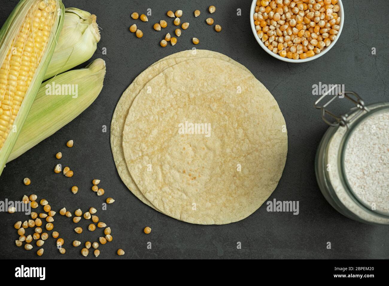 Fresh baked tortilla bread, corn flour in jar, corn kernel in bowl and ...
