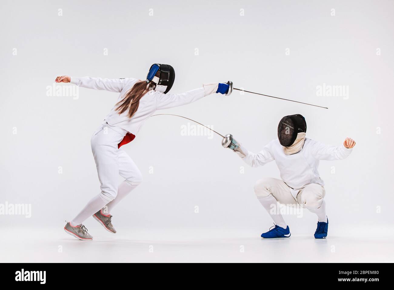 The woman and man wearing fencing suit practicing with swords against ...