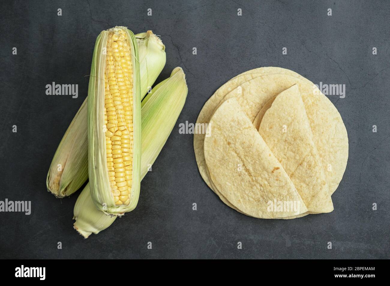 Fresh baked tortilla bread and green corn cobs on concrete, stone ...