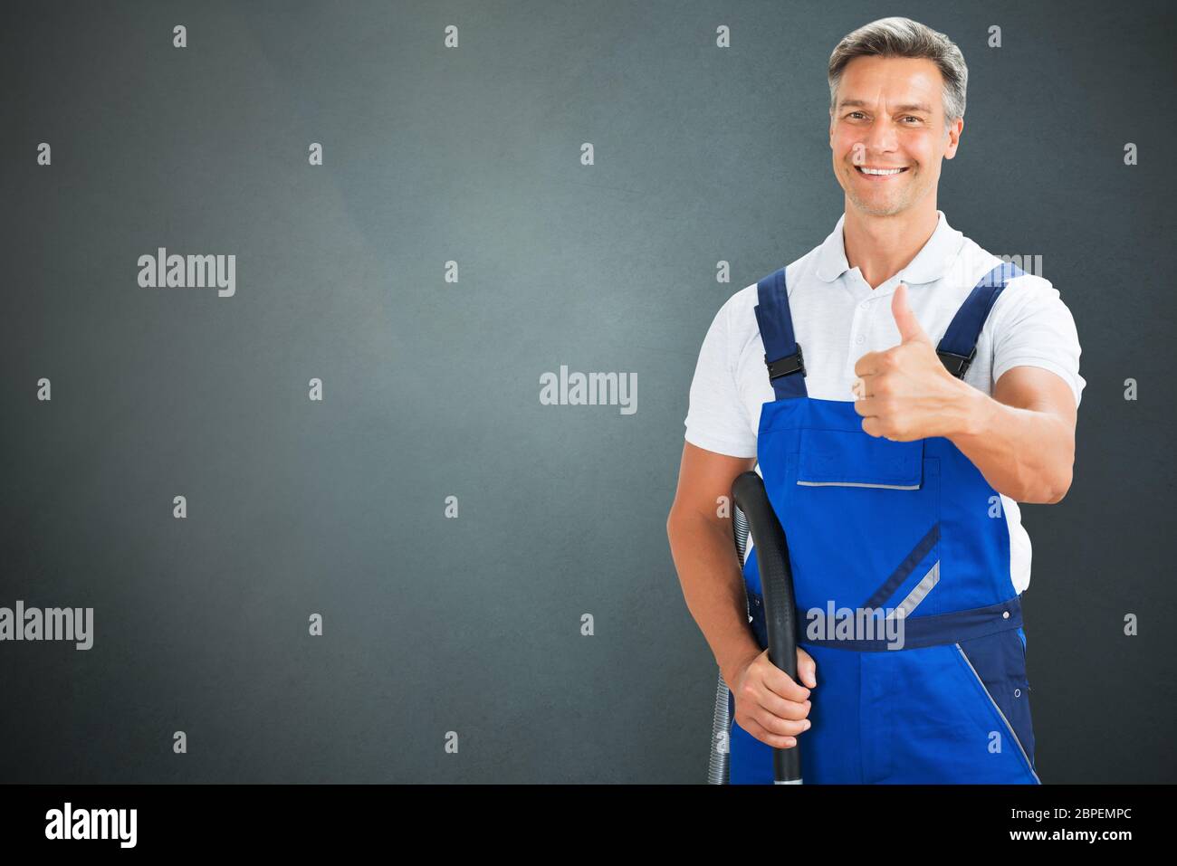 Portrait Of A Smiling Mid Adult Male Janitor Standing Against Gray ...
