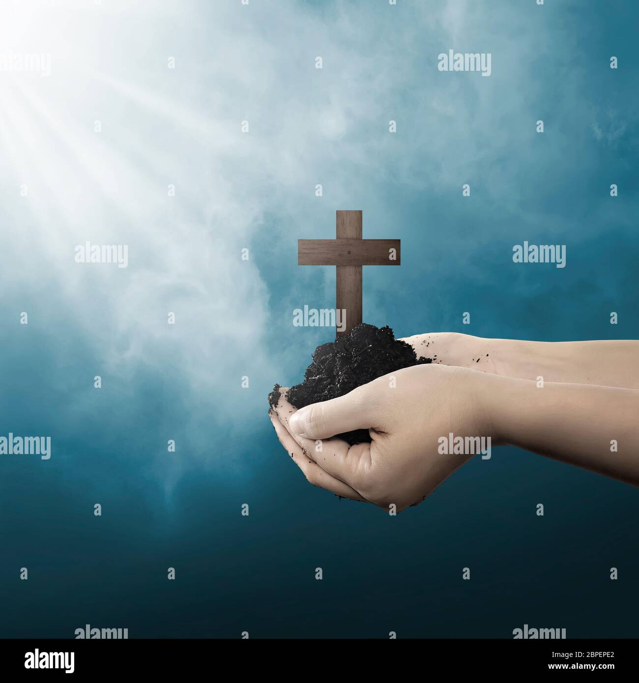 Human hand holding christian cross with soil on the hand over blur ...