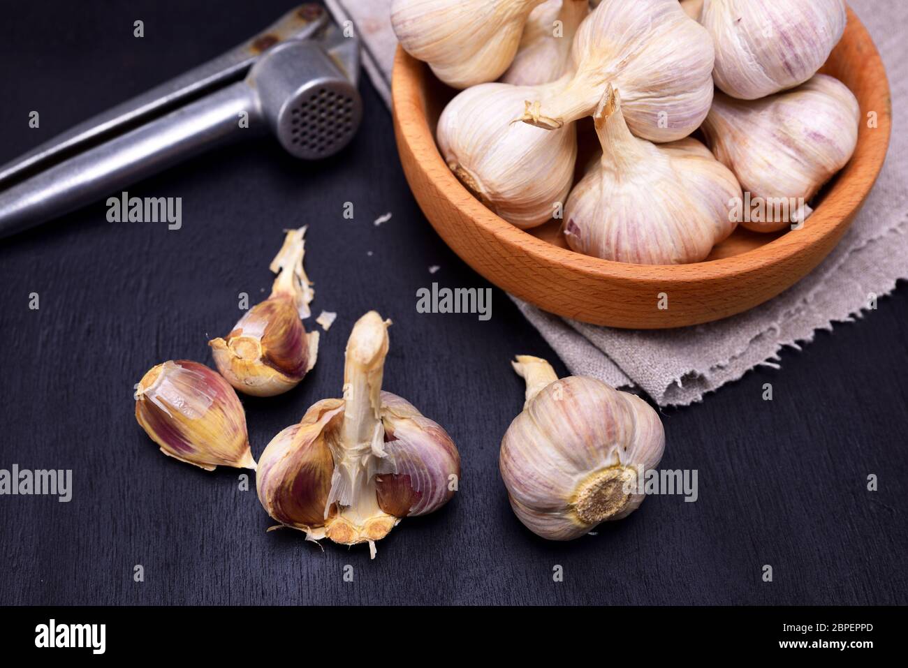 garlic in a wooden bowl and on a black table, top view Stock Photo - Alamy
