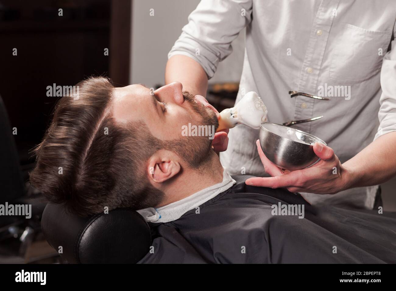 Hipster client visiting barber shop. The hands of young barber making ...