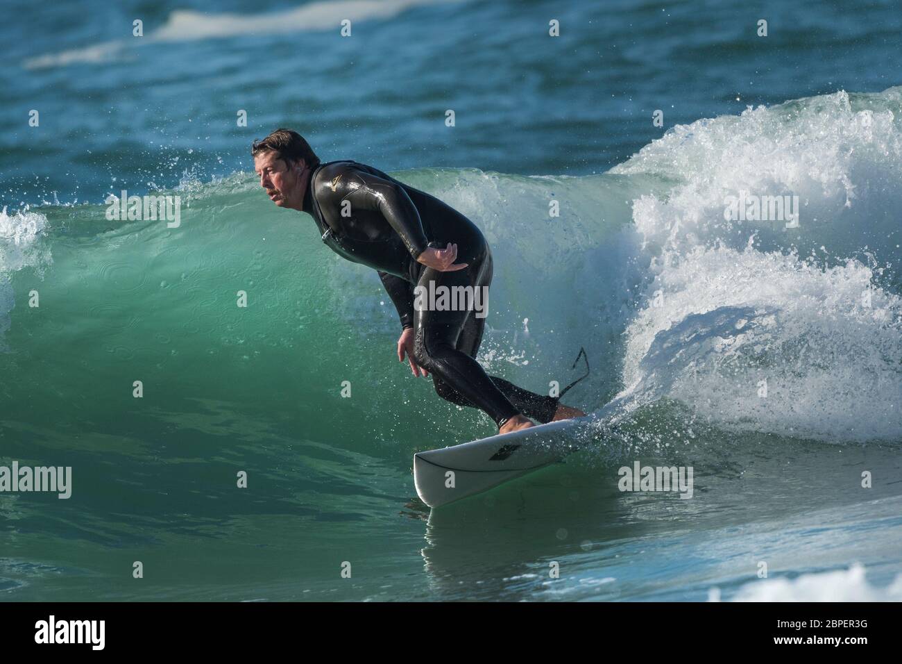A mature male surfer riding a wave at Fistral in Newquay in Cornwall ...
