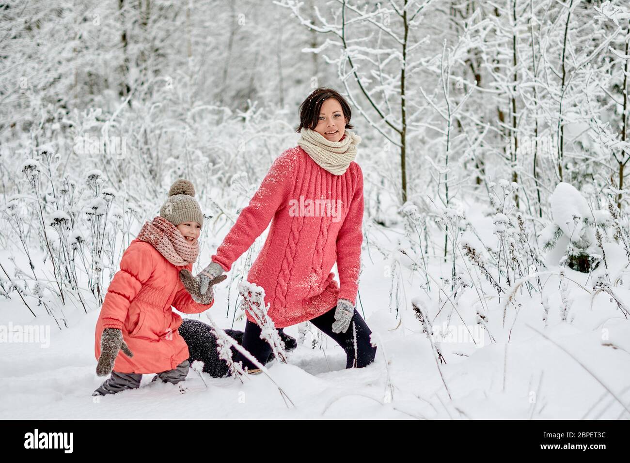 Mom with a little daughter spend a day off in the winter forest. They ...