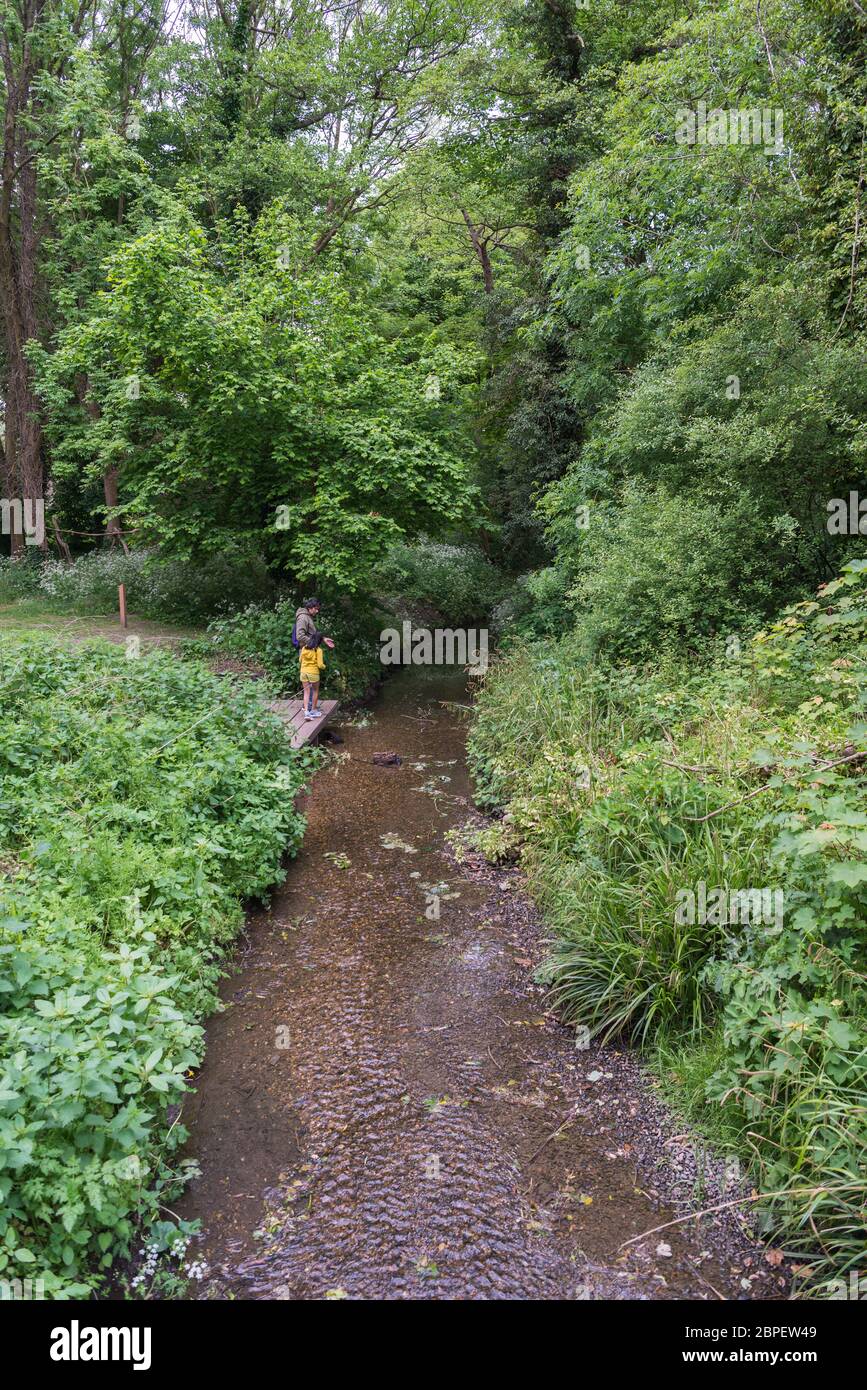 A man and female child stand in conversation on a wooden pontoon on the ...
