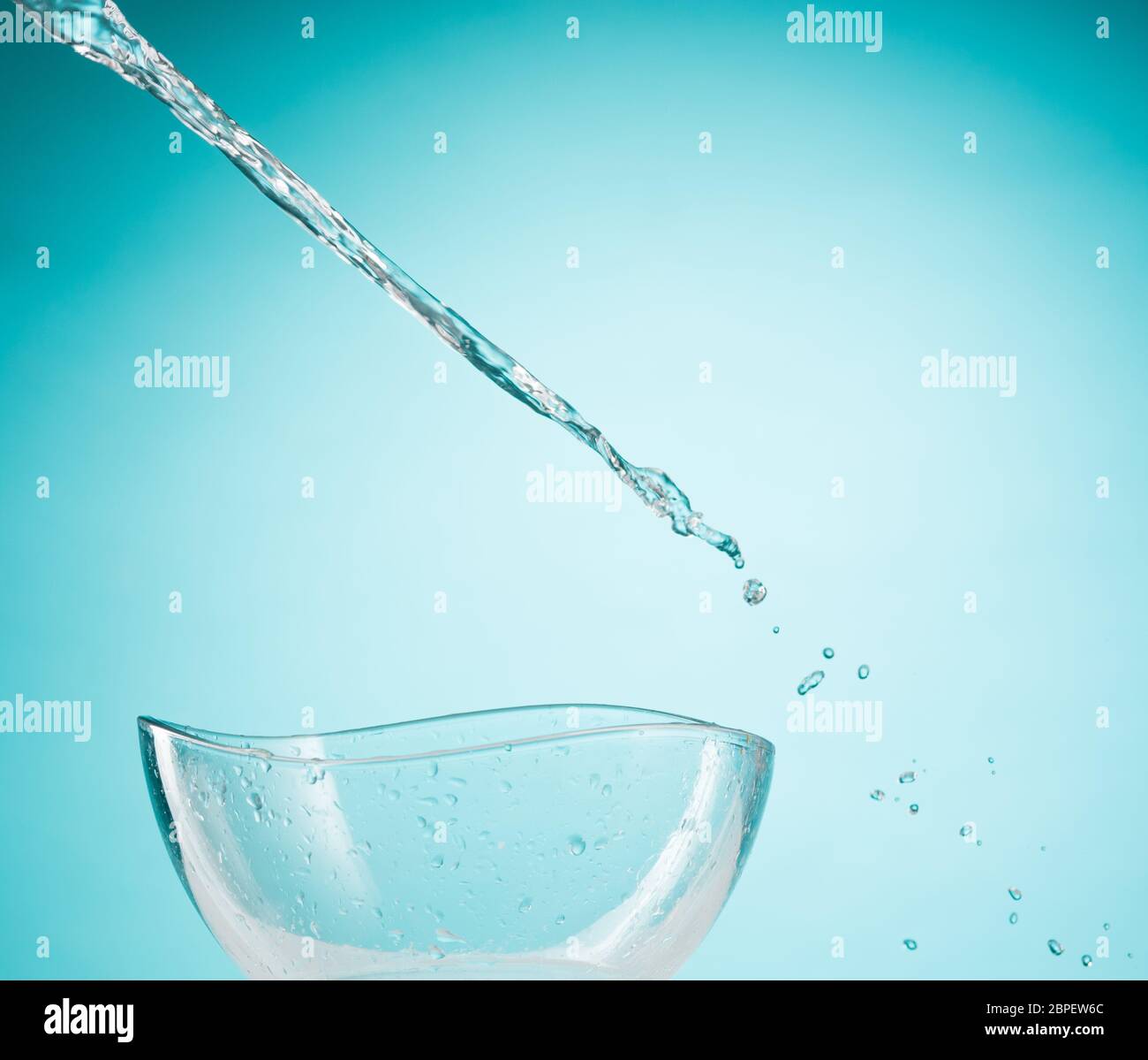 The water splashing inro glass bowl on white background Stock Photo - Alamy