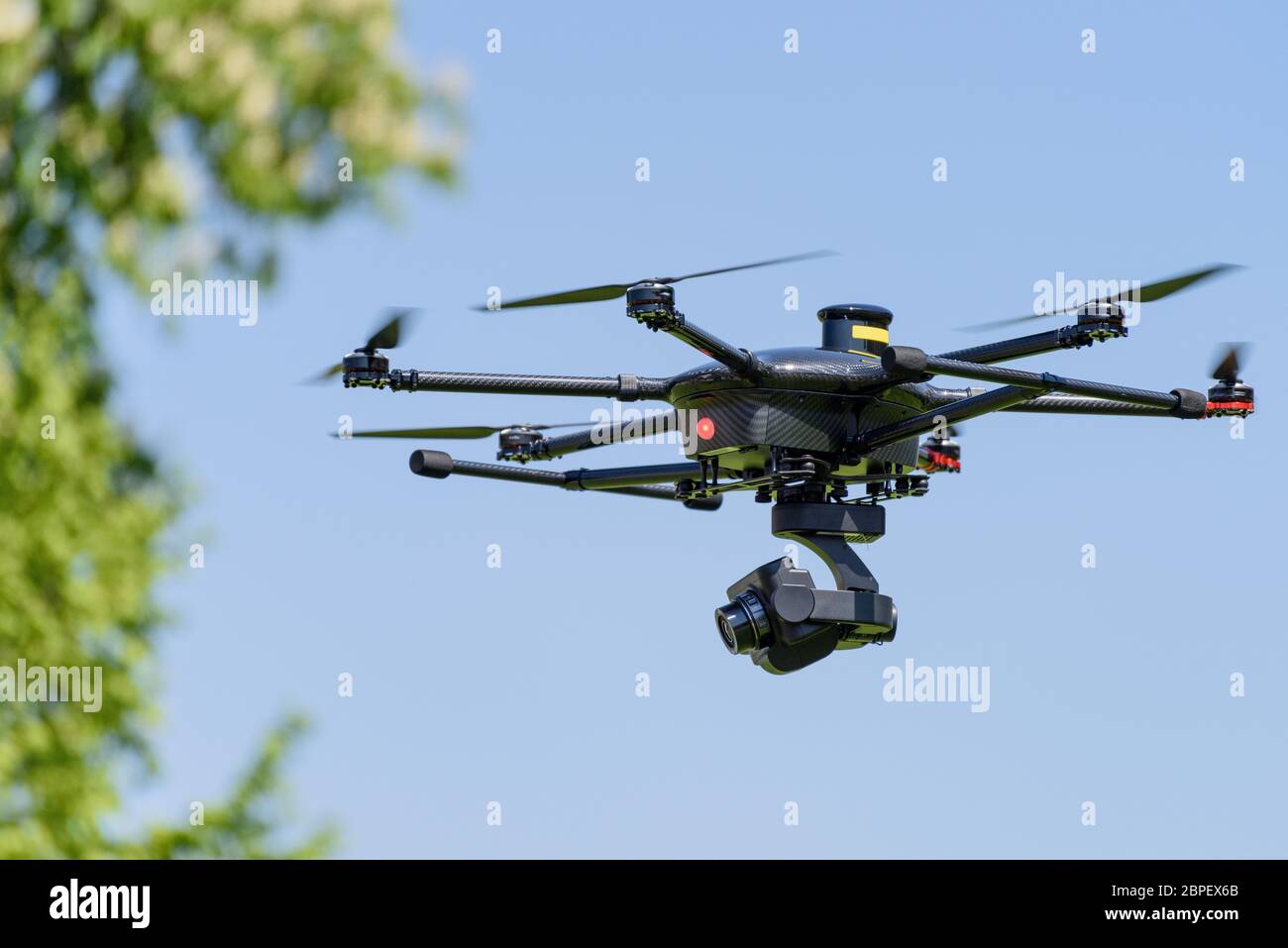 uav drone copter isolated against blue sky approaching a tree Stock ...